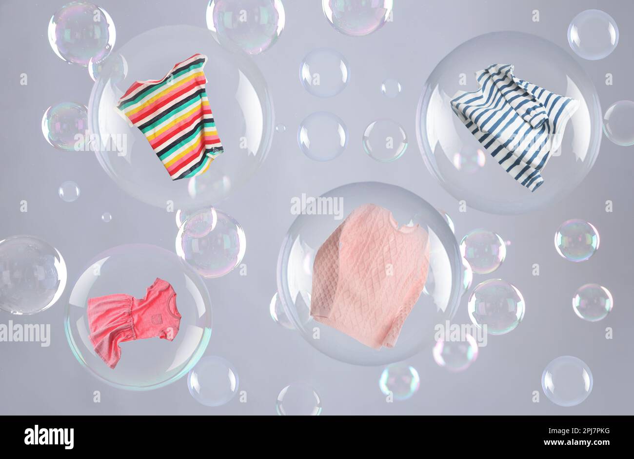 Washing powder bubbles with clothes against grey background Stock Photo ...