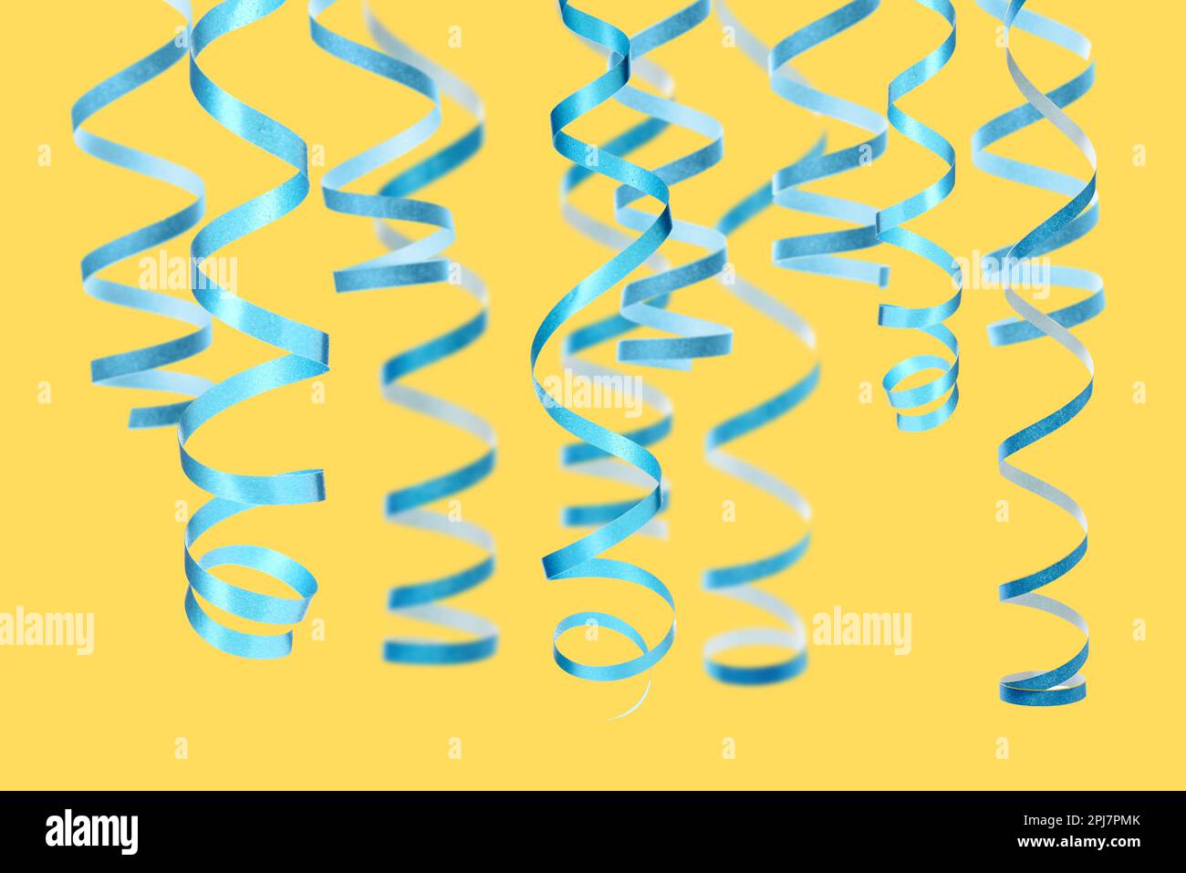 Many light blue serpentine streamers on yellow background. Party decor ...
