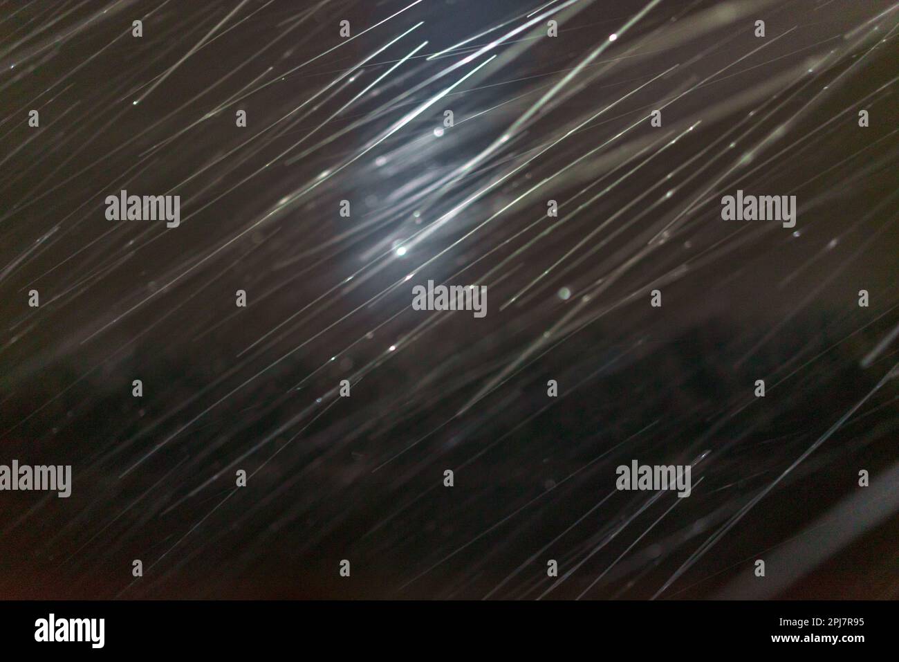 Falling snow at night in the dark in a beam of light against the ...