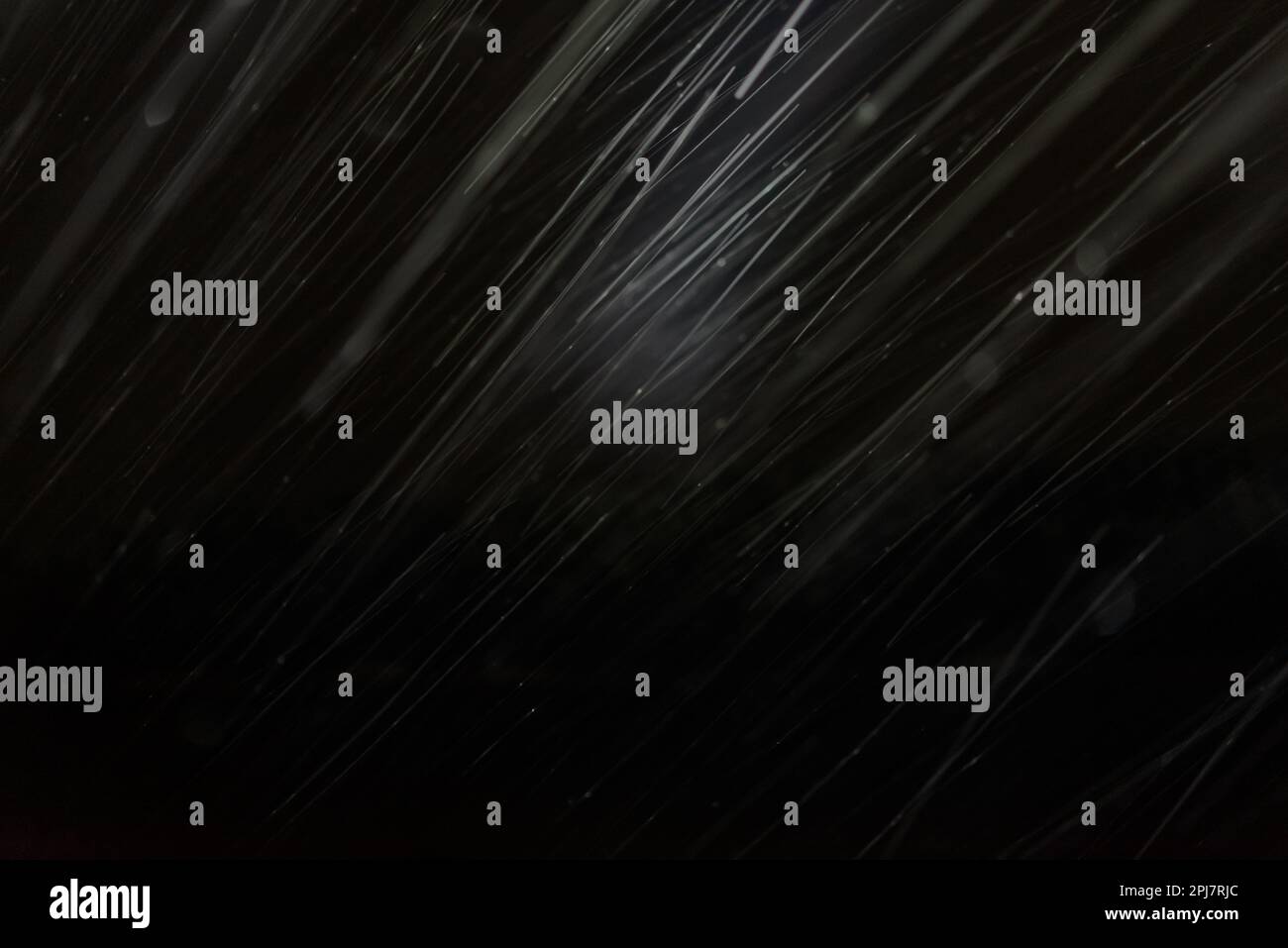 Falling streaks from white snow falling at night in the dark in winter ...