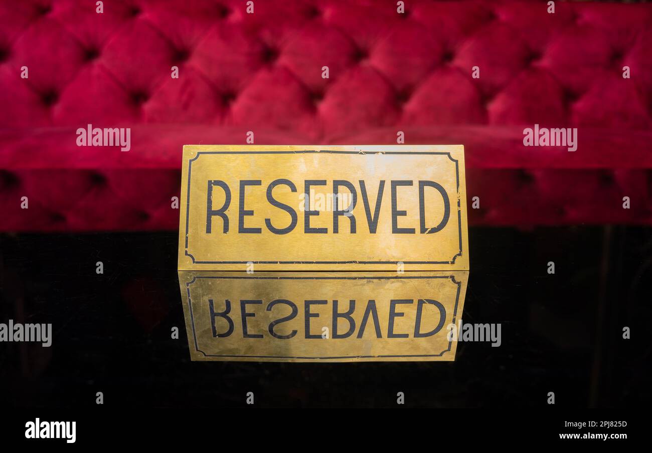 A gold metal sign on a black table that reads "reserved" in front of a ...