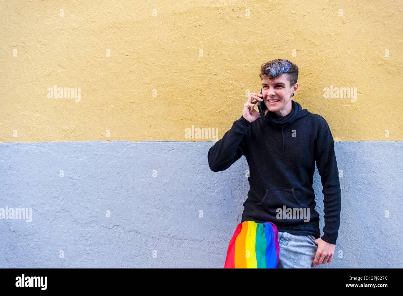 Non binary person with an lgbt rainbow flag talking on the phone ...
