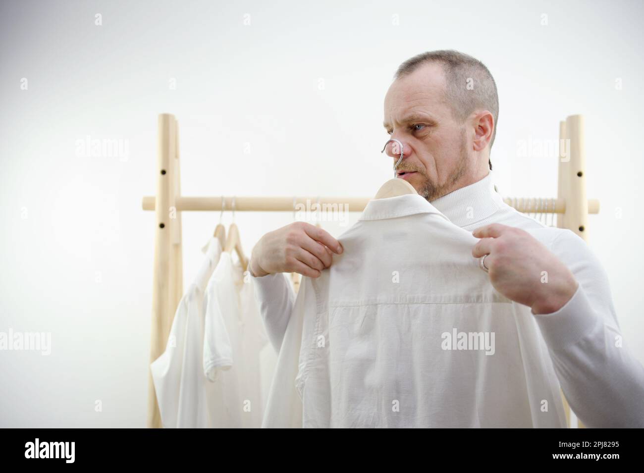 man isolated in front of white background holding two shirts. man can't ...