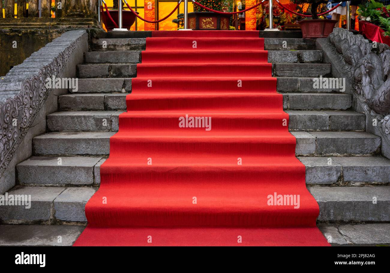 View from below of a rolled out red carpet on a stone staircase. The ...
