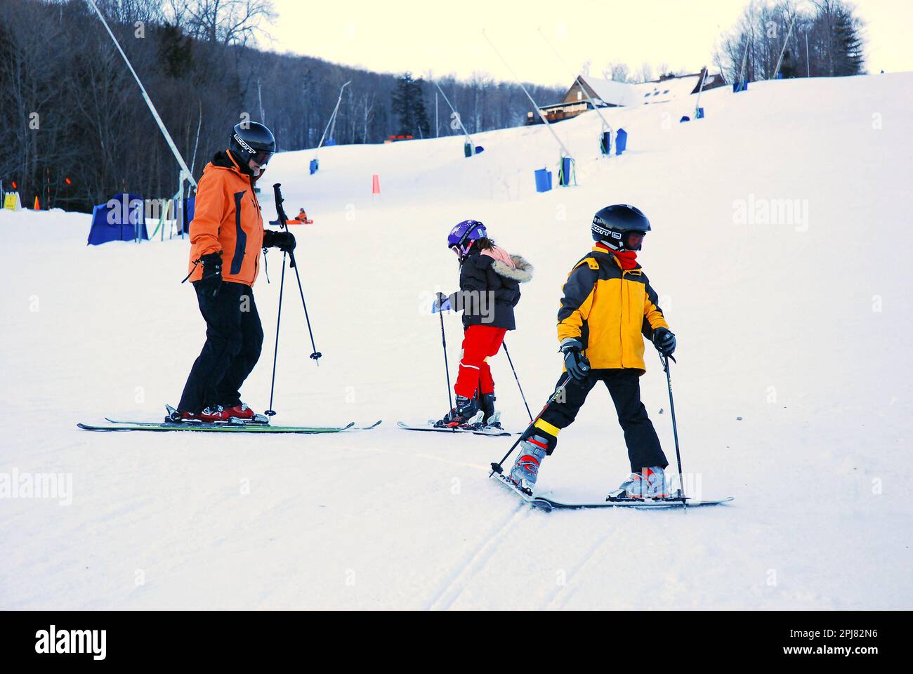 A father teaches his son and daughter to ski on the smaller hills Stock ...