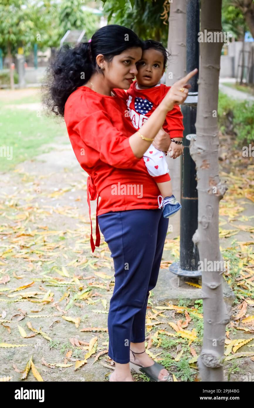 Loving mom carrying of her baby at society park. Bright portrait of ...