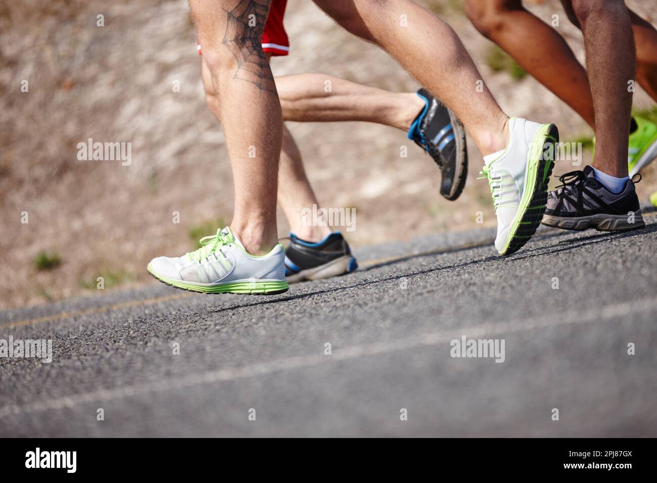 Pacing each other. the legs of a group of men running a road race Stock ...