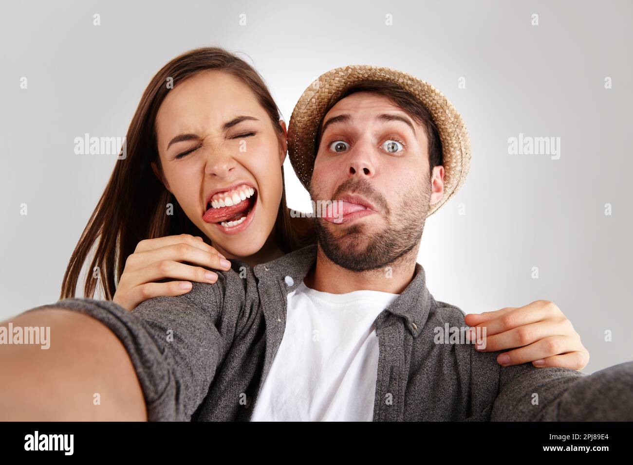 Feeling silly. Self portrait of a happy young couple in studio pulling ...