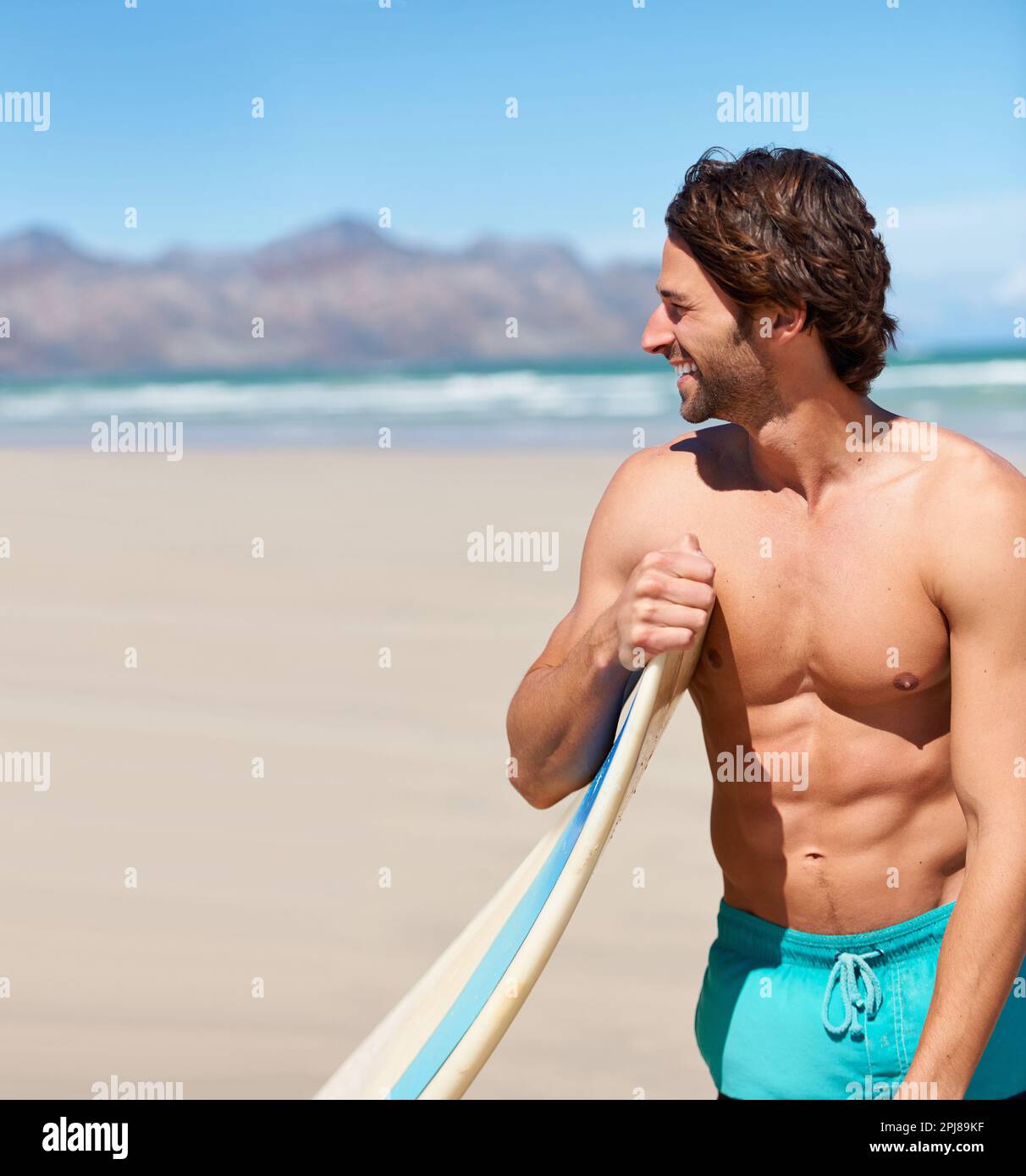Surfing keeps him in great shape. A young man standing next to his ...