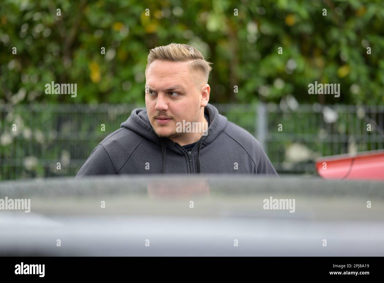 Young man with a mustache and unshaven with a stylish haircut stands in ...