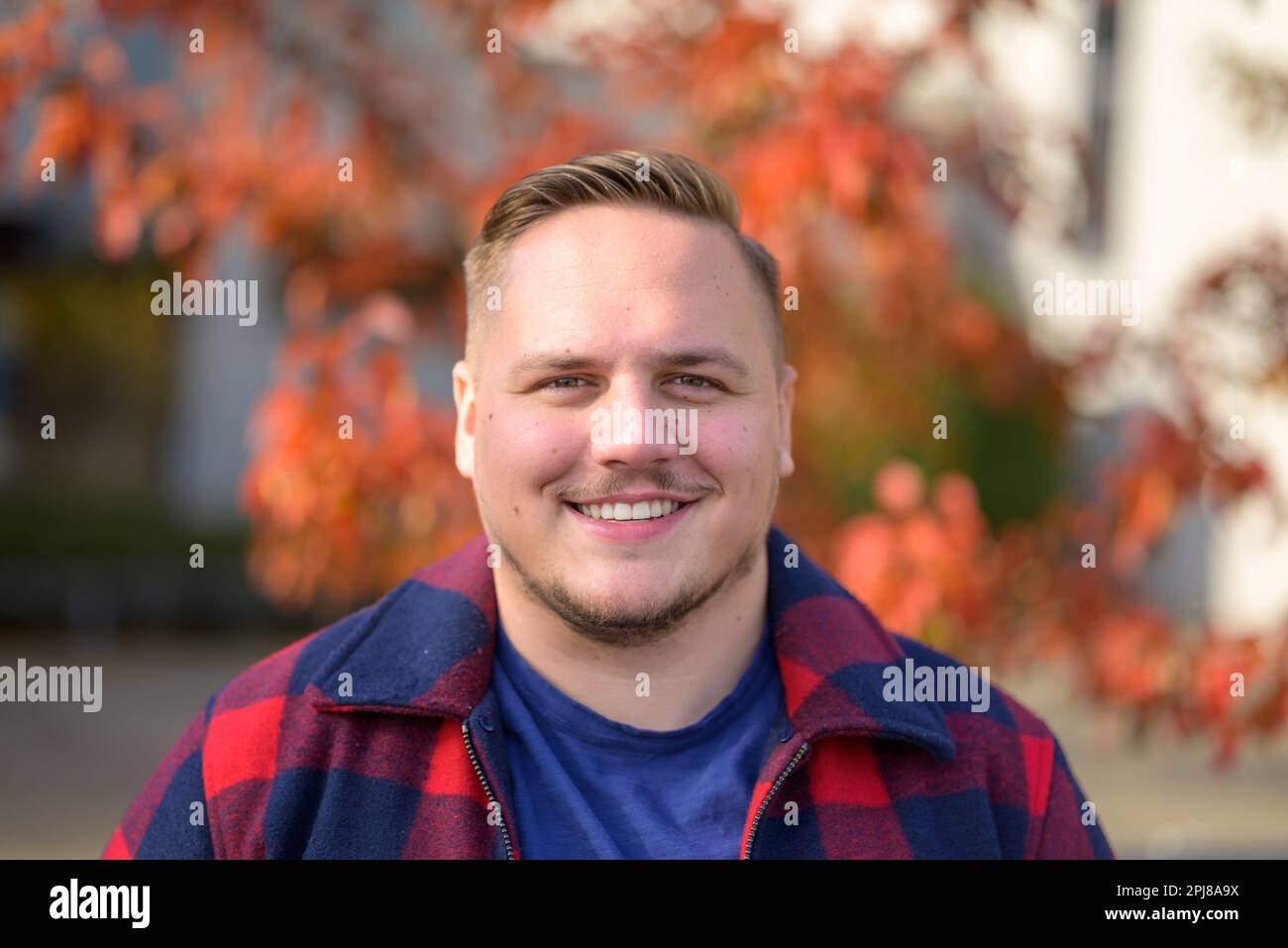 Portrait of an young man with a bright smile in a peasant jacket stands ...