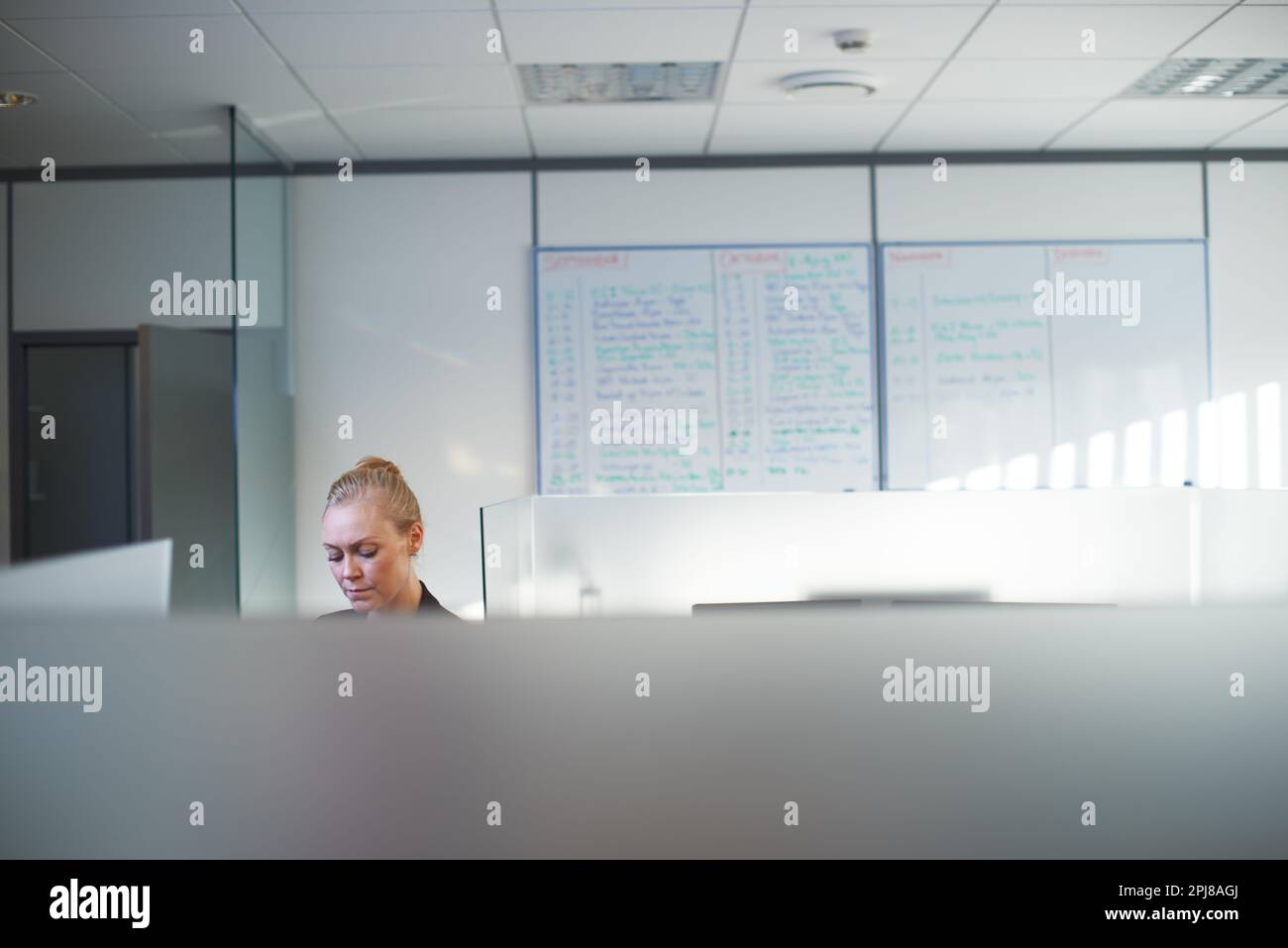 Working in her cubicle. an attractive young woman standing in her ...