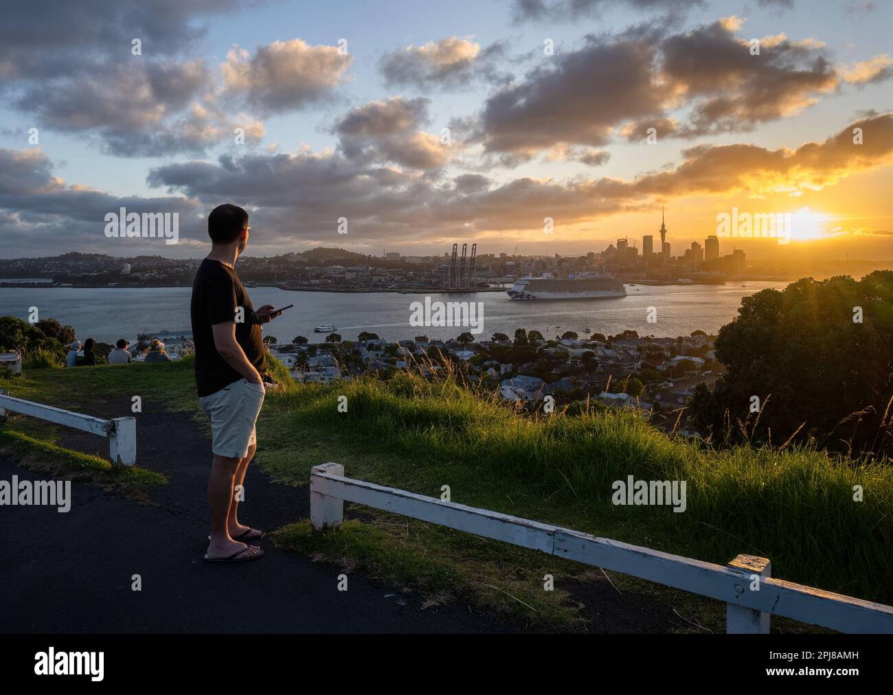 Tourists watching sunset over Auckland city with cruise ship sailing ...