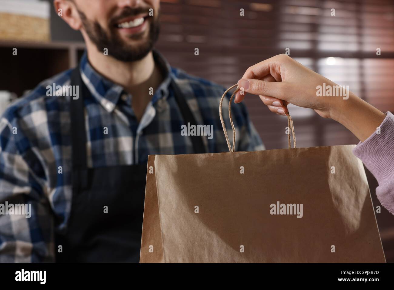 Worker giving paper bag to customer in cafe, closeup Stock Photo - Alamy