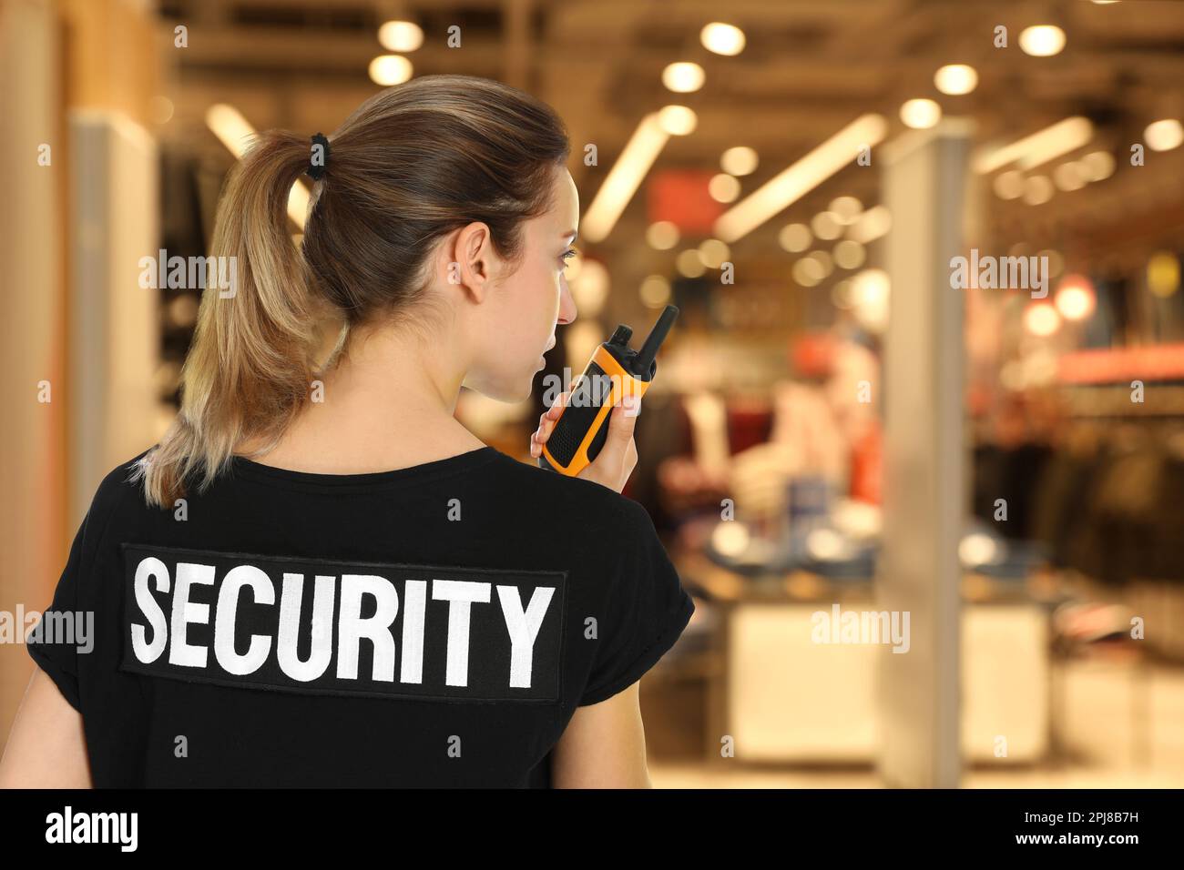 Female security guard wearing uniform using portable radio transmitter ...