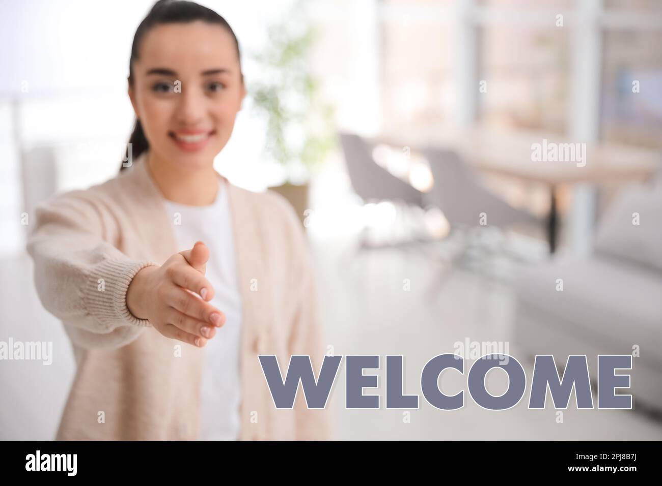 Happy young woman offering handshake indoors, focus on hand. Welcome to ...