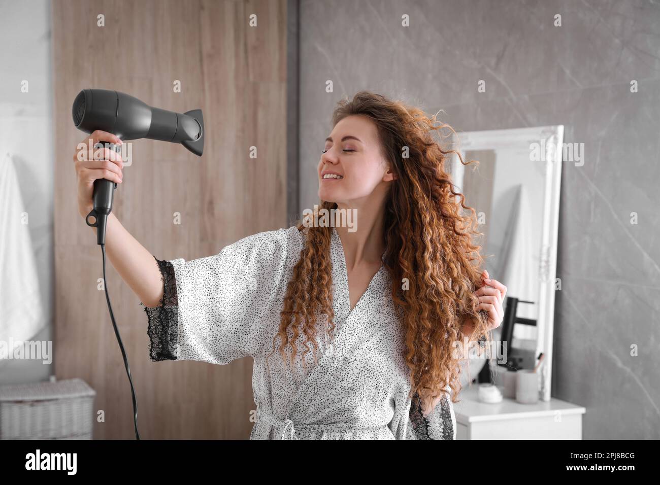 Beautiful woman using hair dryer in bathroom Stock Photo - Alamy