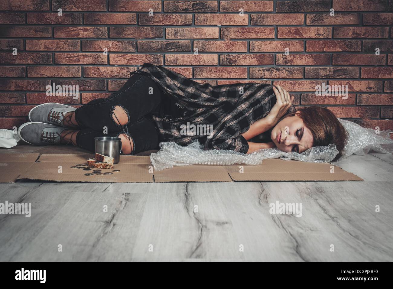 Poor homeless woman sleeping on floor near brick wall Stock Photo - Alamy