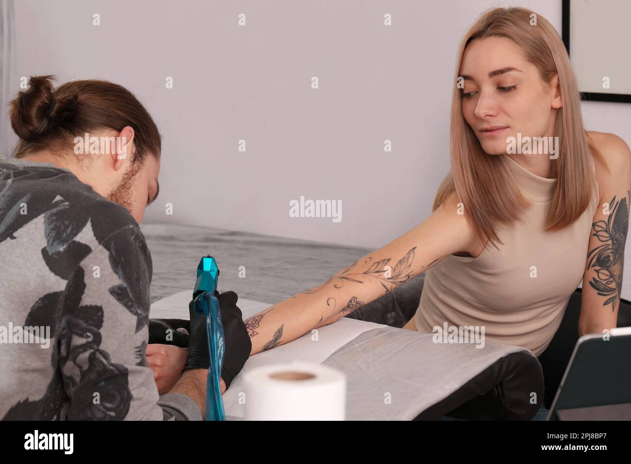 Professional artist making tattoo on arm in salon Stock Photo - Alamy