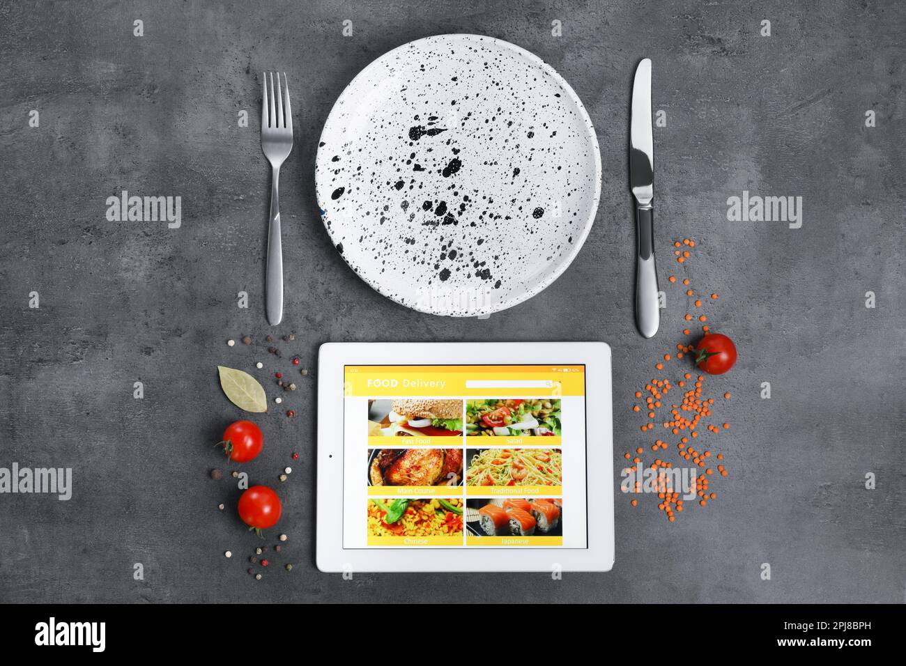 Modern tablet with open page for online food ordering, scattered ...