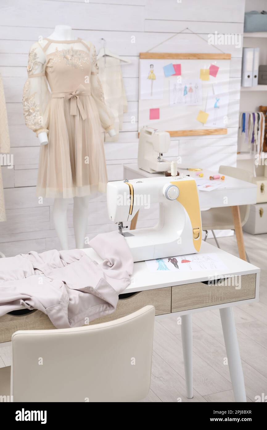 Modern sewing machine with fabric on table in dressmaking workshop ...