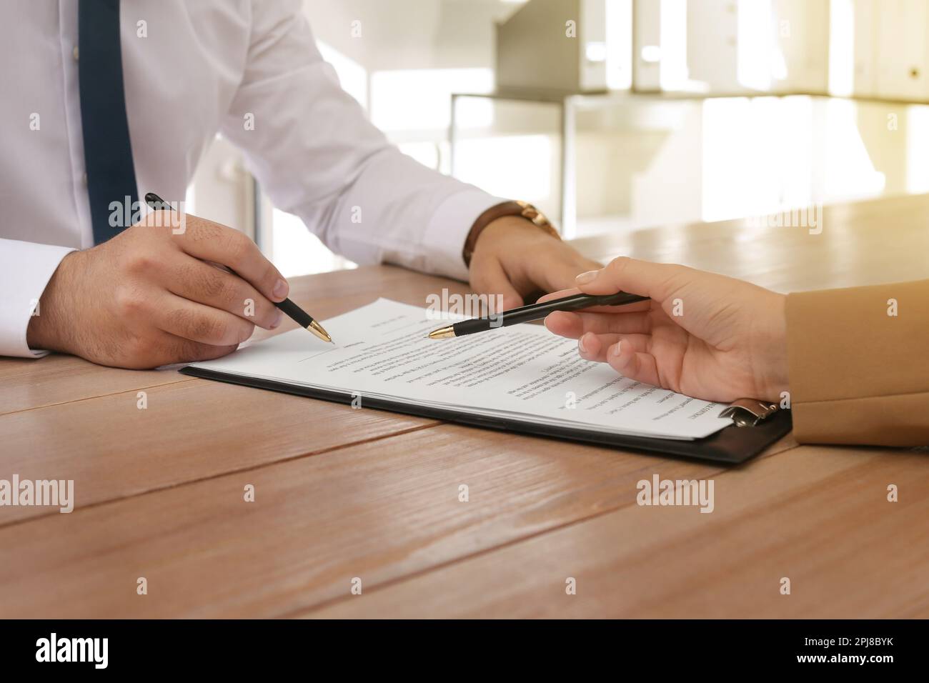 Man signing document at wooden table in office, closeup. Insurance ...