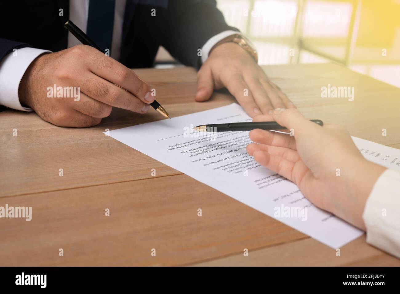Man signing document at wooden table in office, closeup. Insurance ...