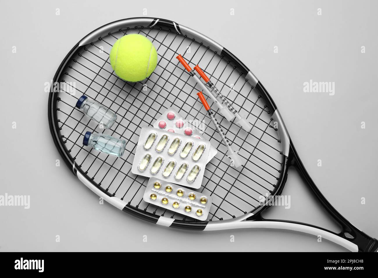 Tennis racket with ball and drugs on light grey background, top view ...