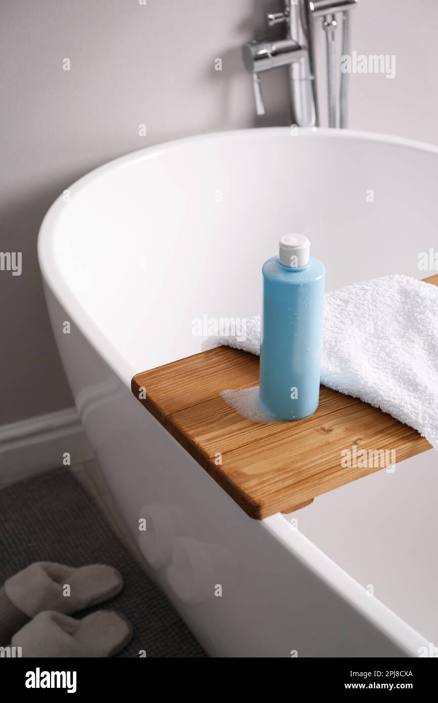 Bottle of bubble bath with foam and towel on tub in bathroom Stock ...