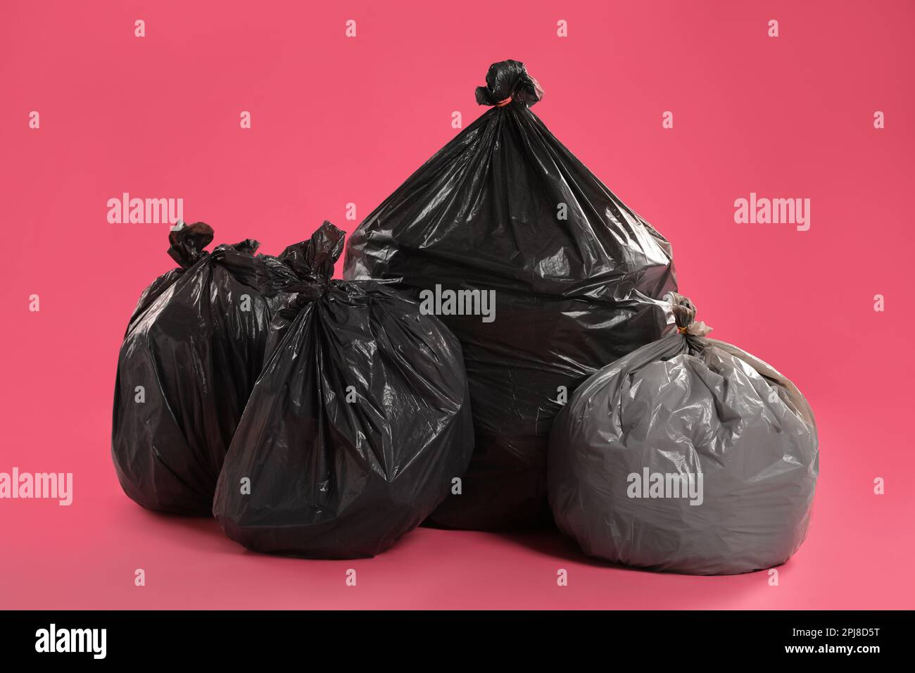 Trash bags full of garbage on pink background Stock Photo - Alamy