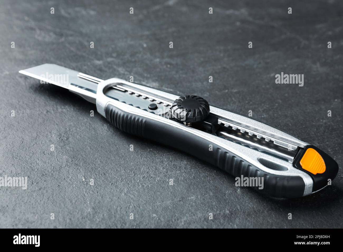 Utility knife on black table, closeup. Construction tool Stock Photo ...