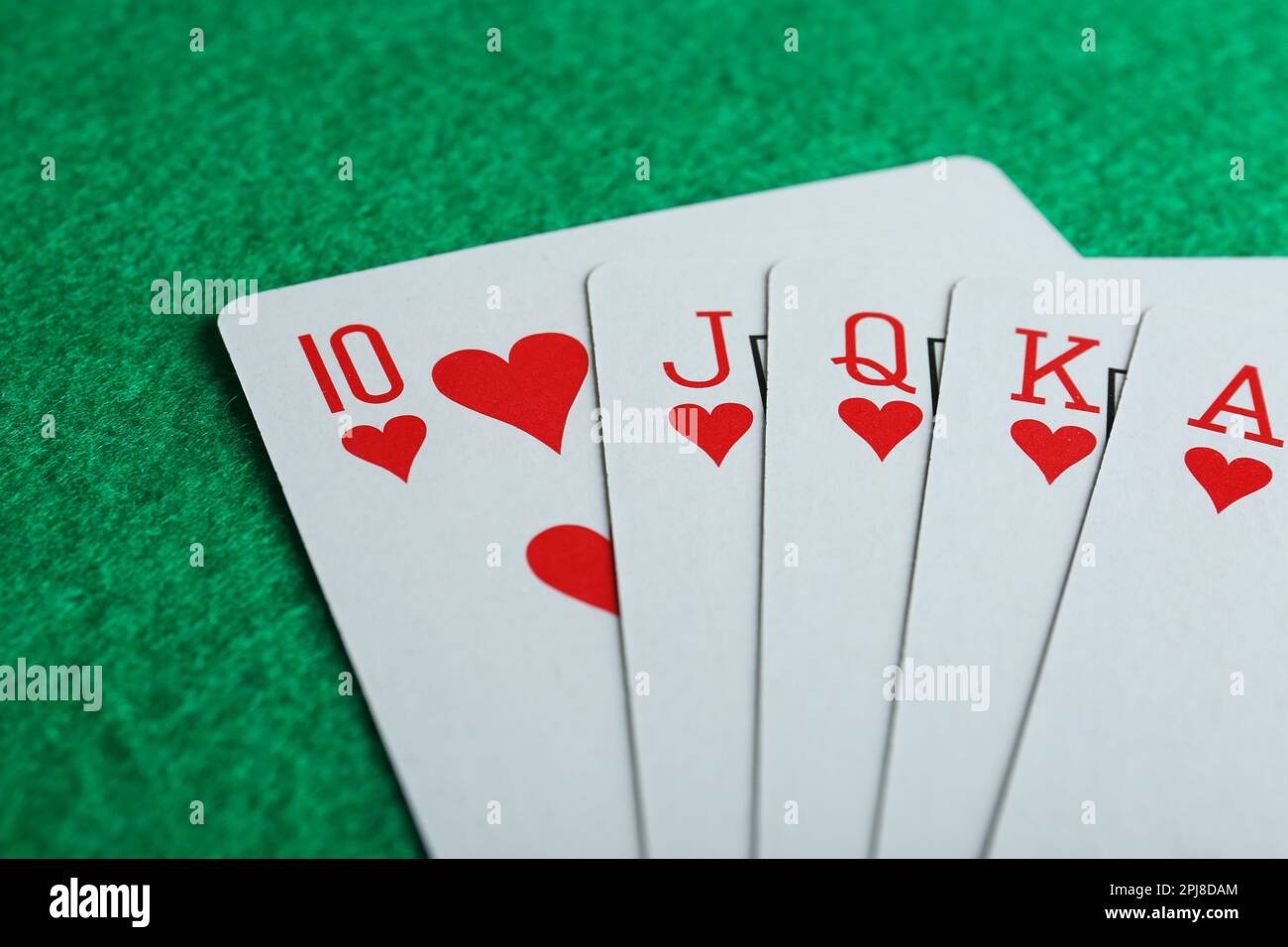 Playing cards with royal flush combination on green table, closeup ...