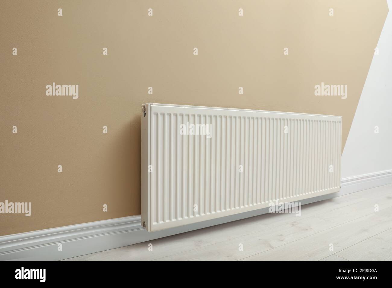 Modern radiator on beige wall indoors. Central heating system Stock ...