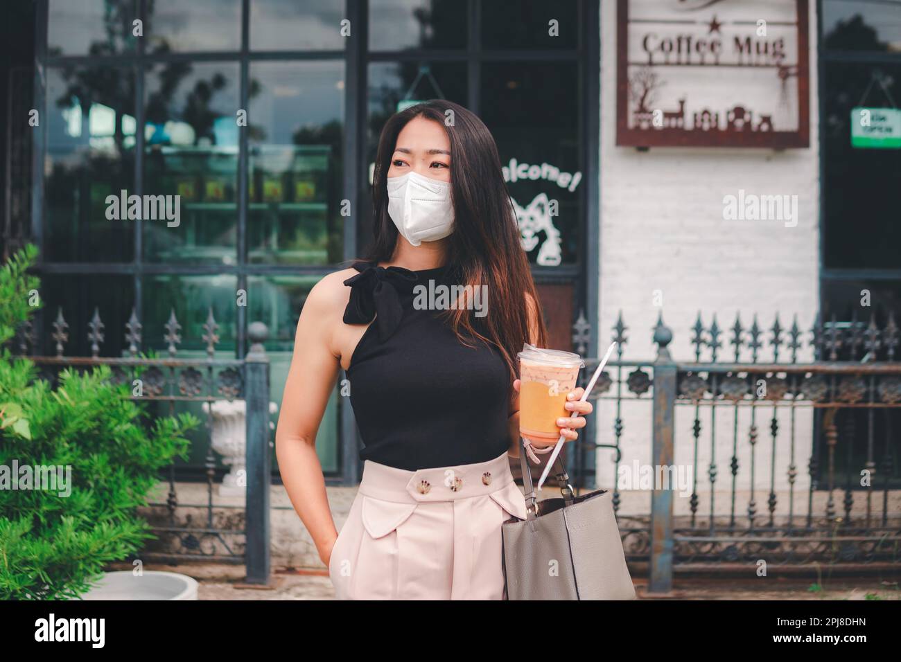 A beautiful asian woman holding glass of coffee open the door walk out ...