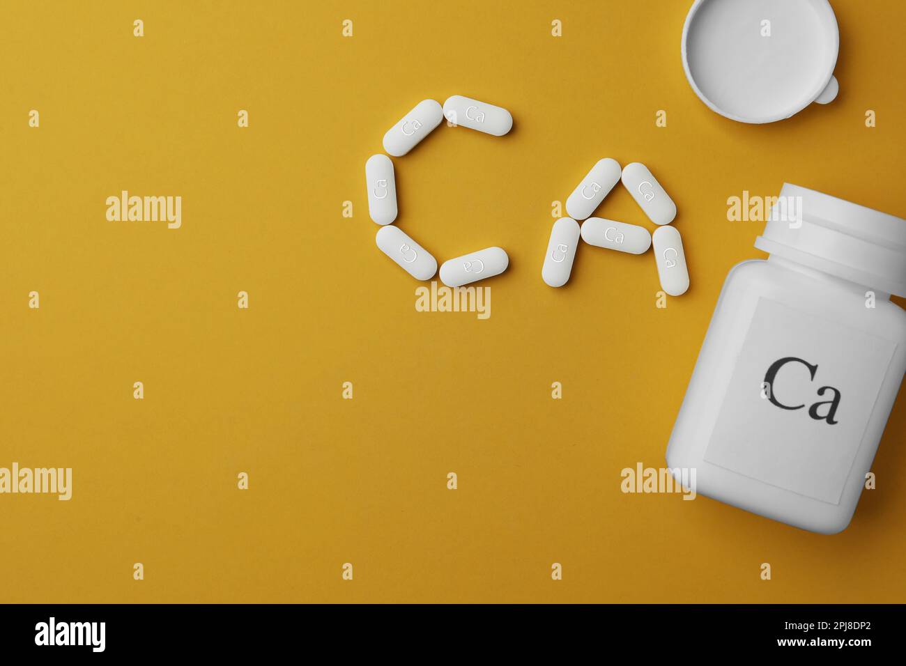 Calcium supplement pills and jar on yellow background, flat lay. Space ...