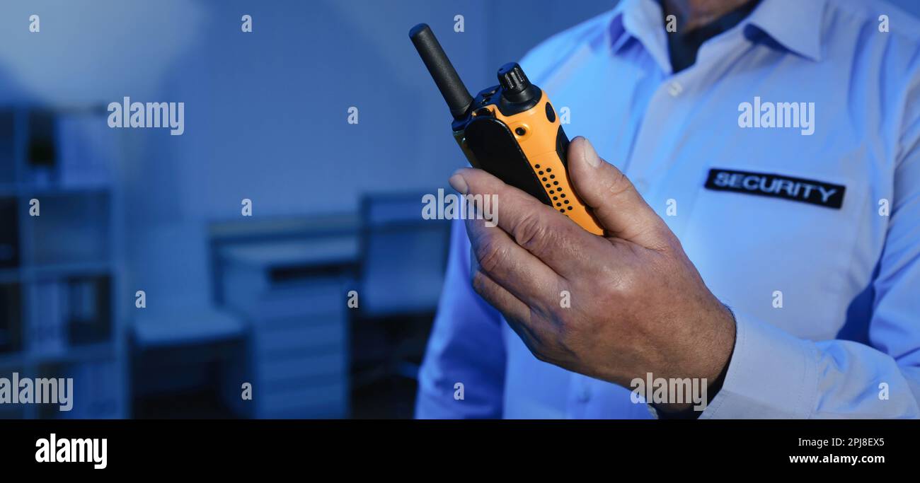 Professional security guard with portable radio set in dark room ...