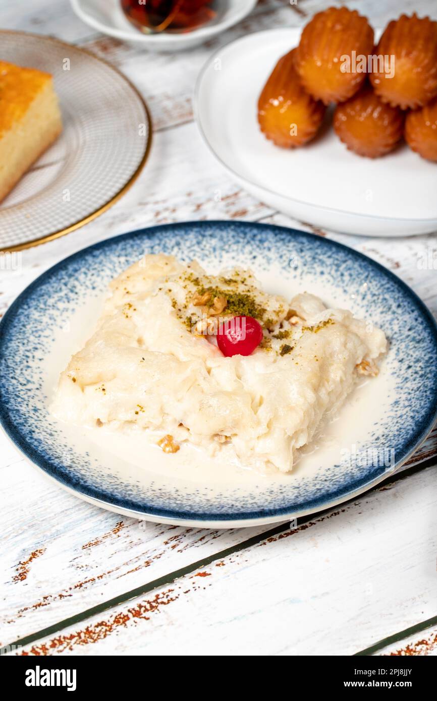Güllaç, revani, tulumba and bread kadayif dessert with cream on a wood ...