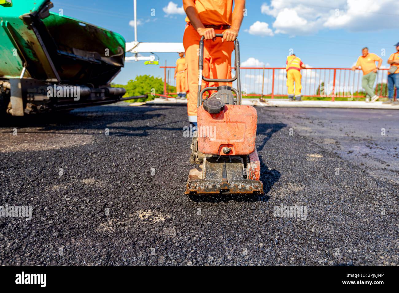 View on worker who is compacting asphalt with vibration plate ...