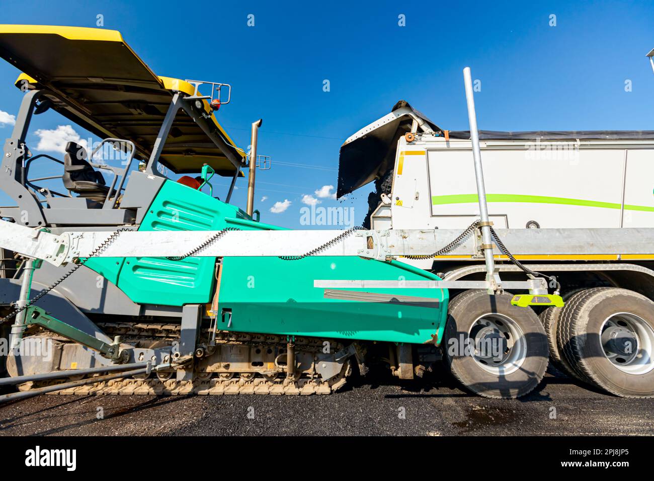 Project is in progress, dumper truck is reloading hot asphalt into ...
