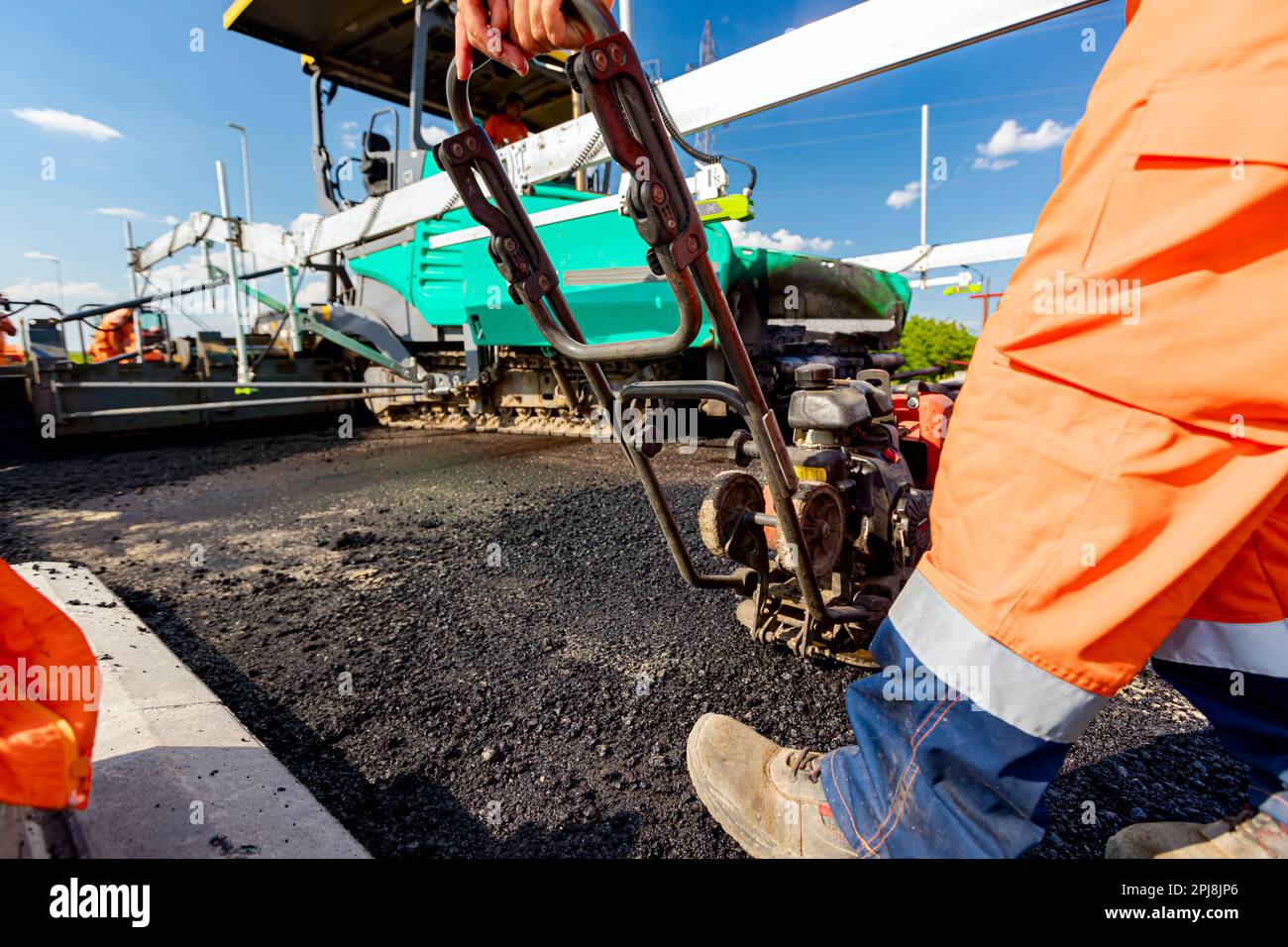 View on worker who is compacting asphalt with vibration plate ...