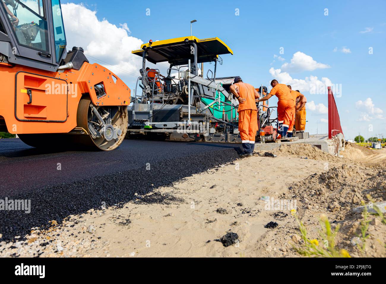 Hot asphalt is spreading with steamroller. Machine for laying asphalt ...