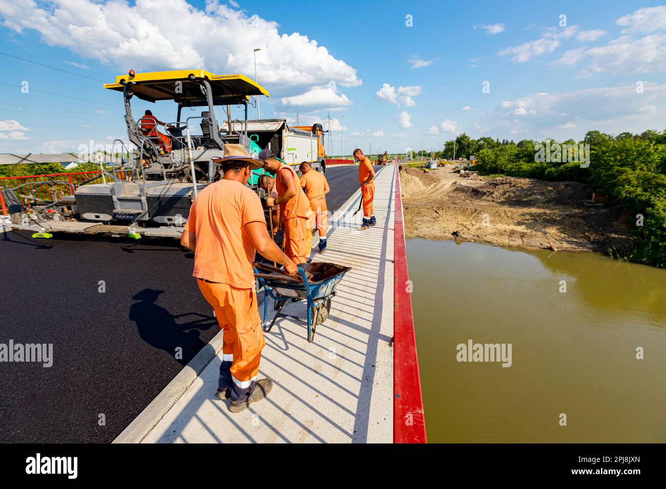 Worker is pushing industrial wheelbarrow over the bridge. Machine for ...