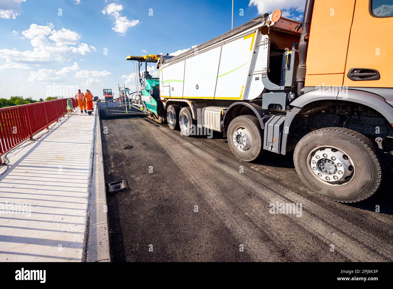 Project is in progress, dumper truck is reloading hot asphalt into ...