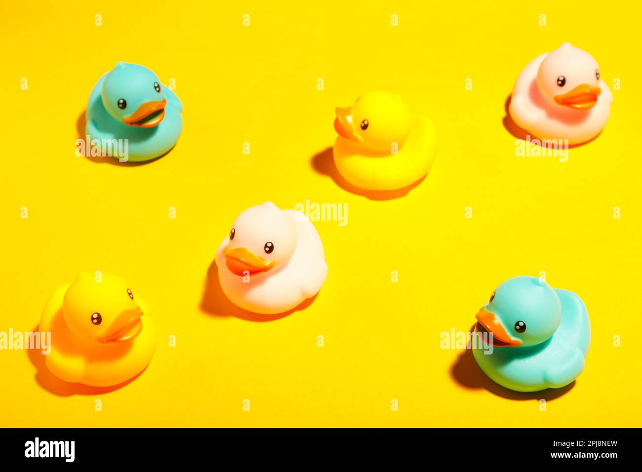 Collection of colorful rubber ducks on a yellow background. Top view ...