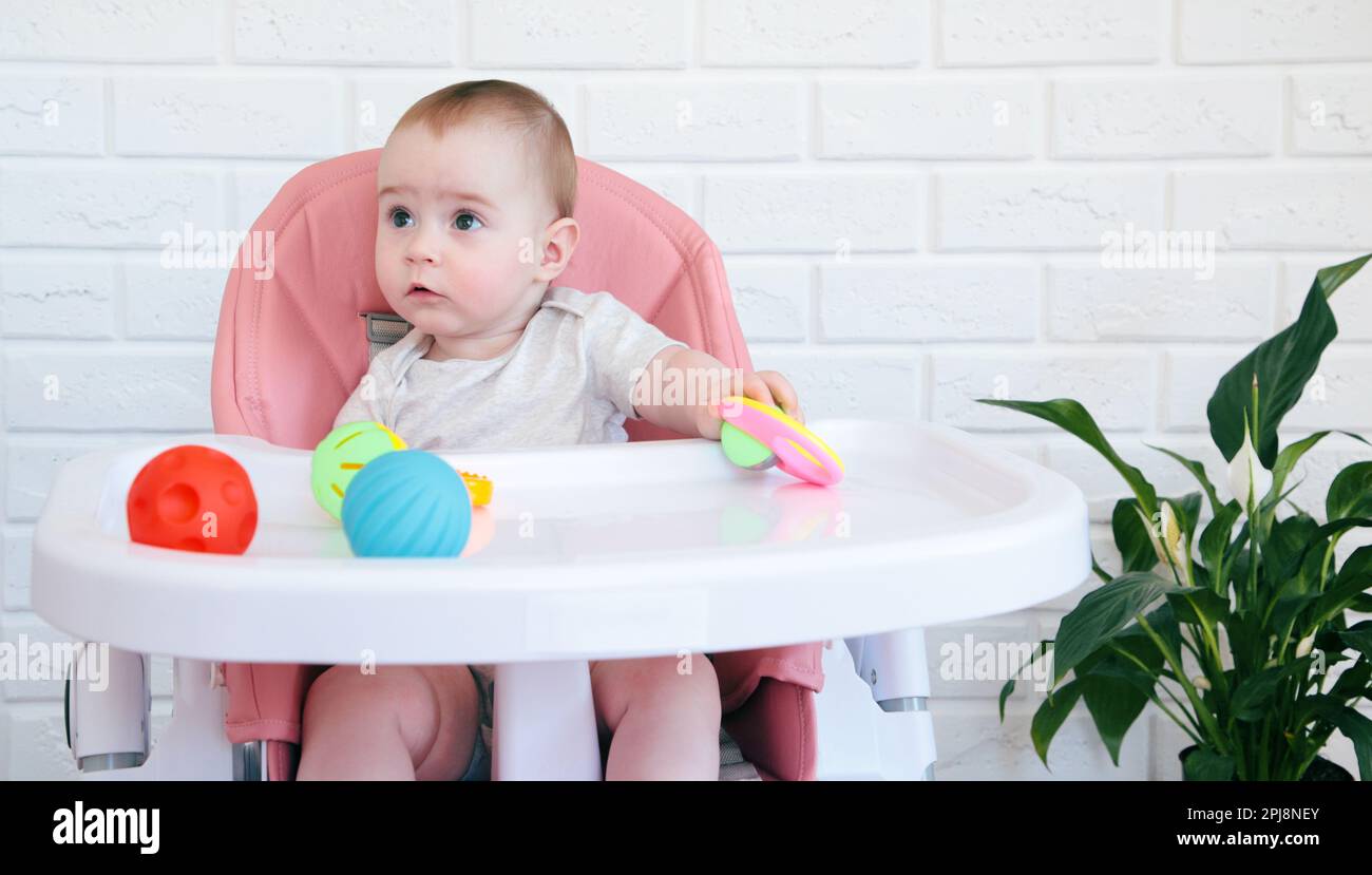 Cute baby girl playing a rattle in chair Stock Photo - Alamy