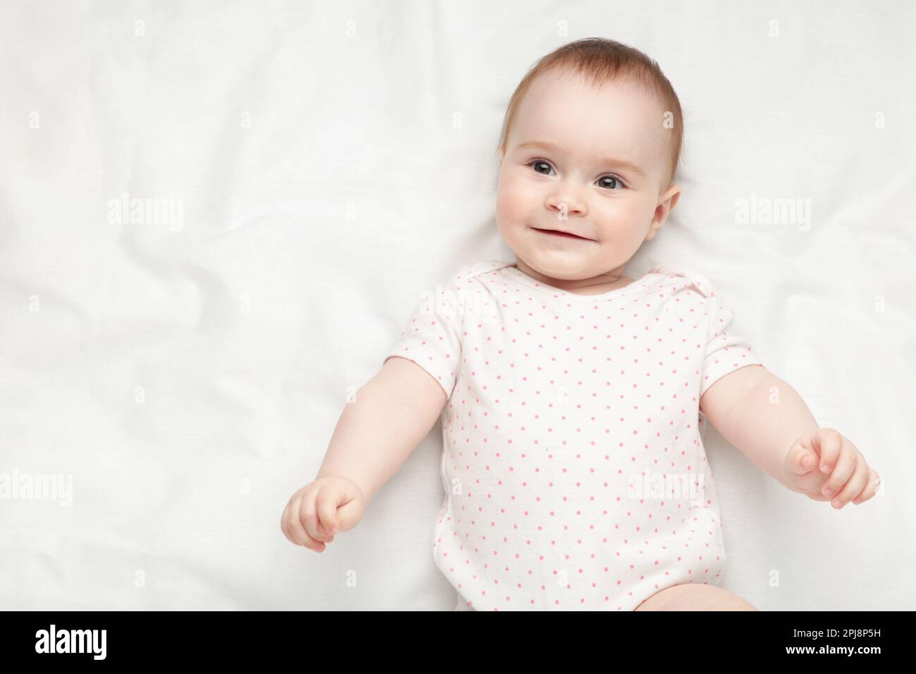 Cute baby girl lying and smile on white bed. Top view Stock Photo - Alamy