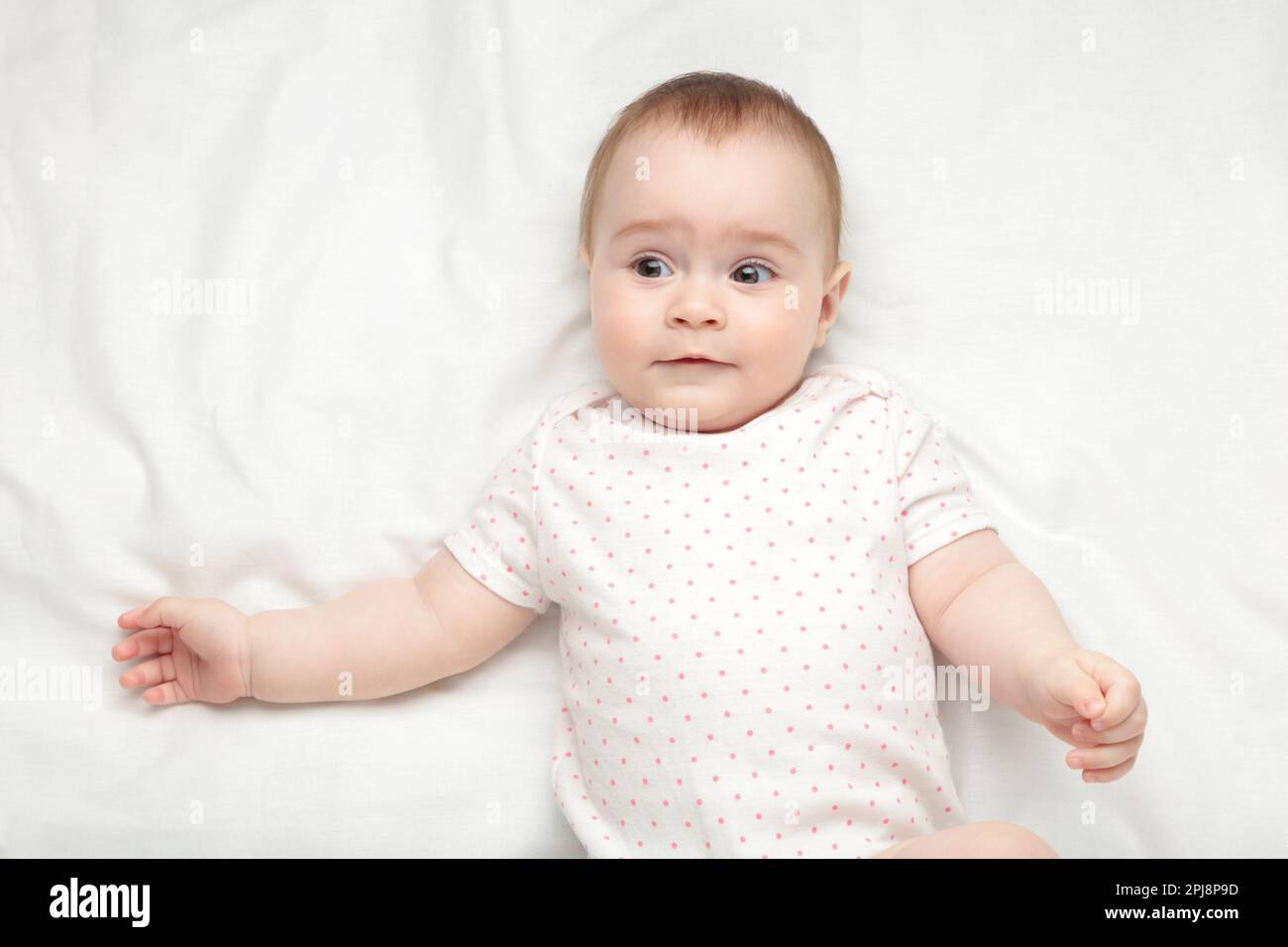 Cute baby girl lying and smile on white bed. Top view Stock Photo - Alamy