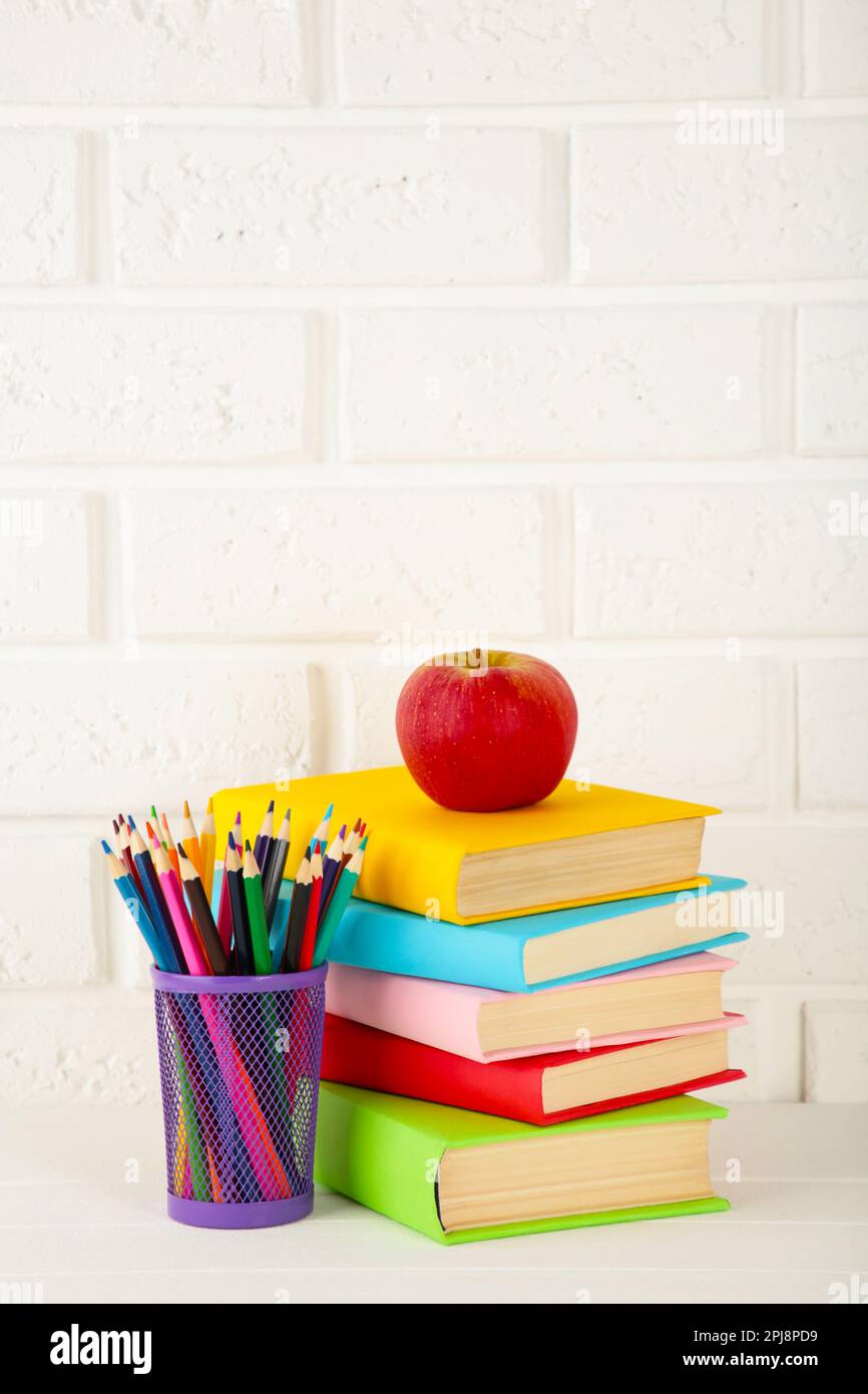Multi coloured school books and stationery on white brick wall ...