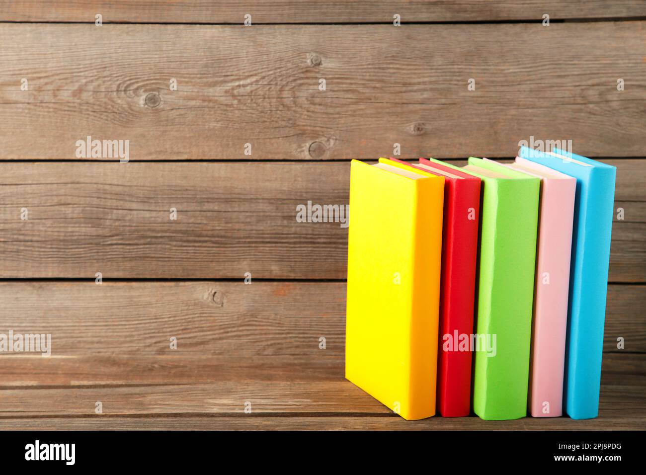 Multi coloured school books on a grey wooden background with copy space ...
