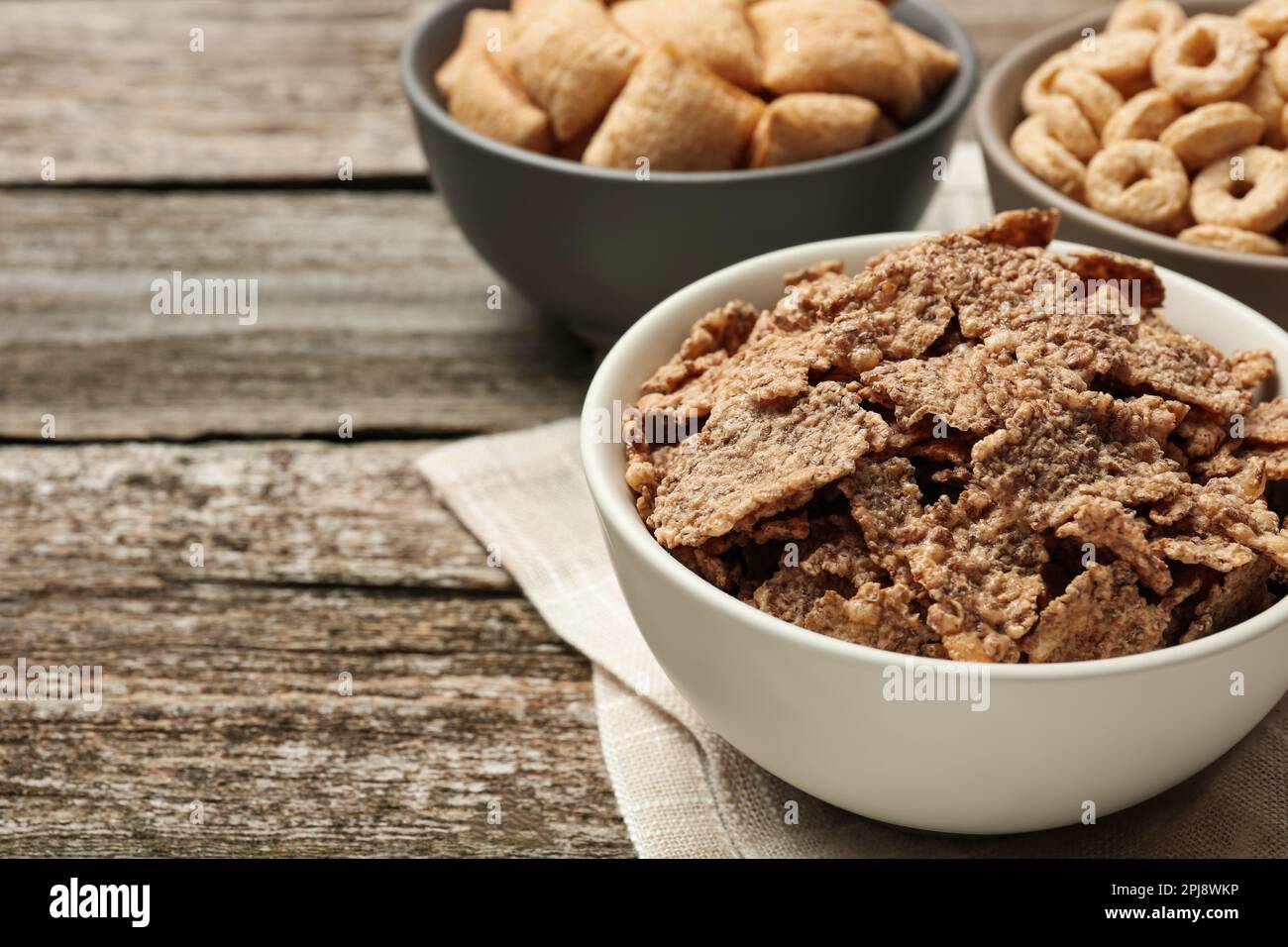 Different breakfast cereals in bowls on wooden table, closeup. Space ...
